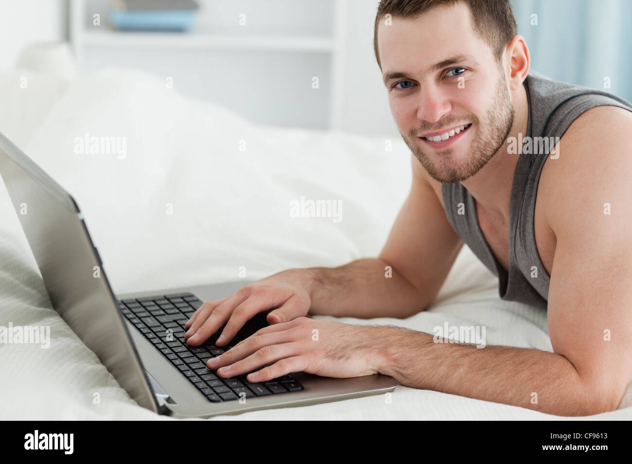 Handsome man using a laptop while lying on his belly Stock Photo - Alamy