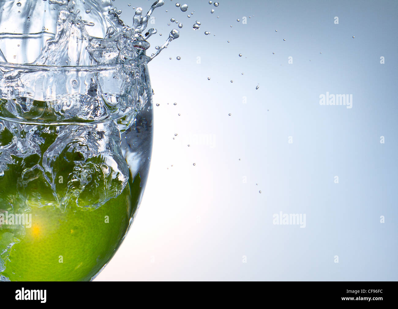 Lime splashing in glass of water Stock Photo - Alamy