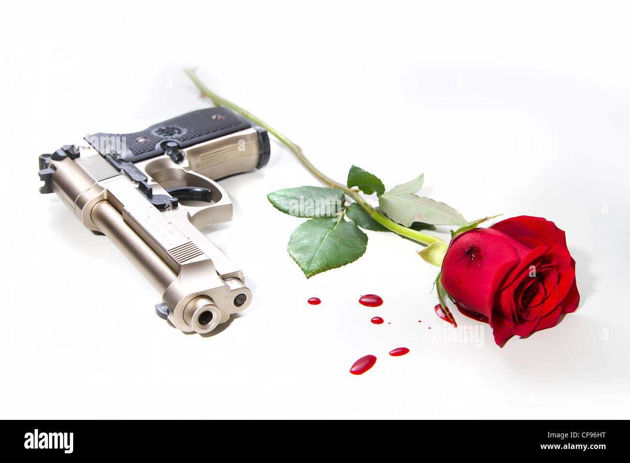 Still life featuring a gun and a wounded rose with some fake blood ...