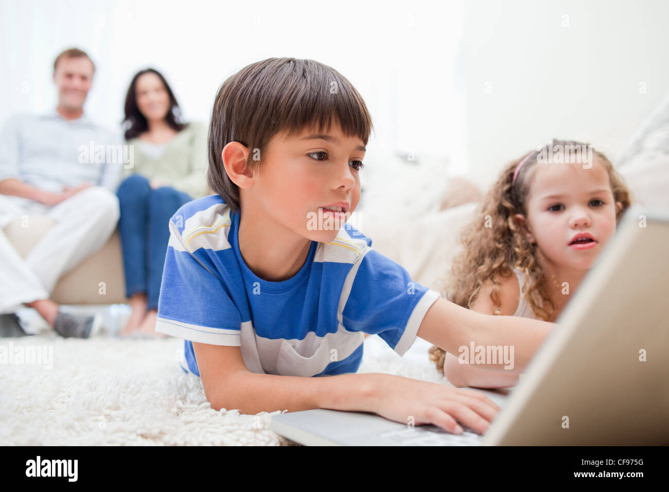 Kids playing computer games on the carpet with parents behind them ...