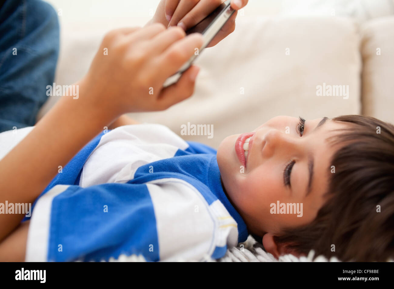 Boy lying on the carpet playing with his cellphone Stock Photo - Alamy