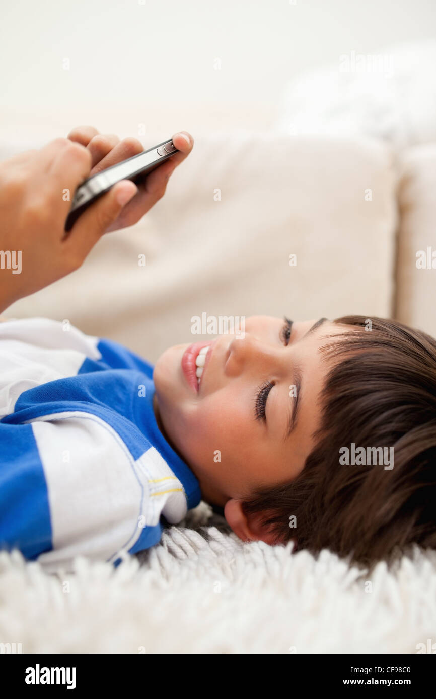 Boy playing with his cellphone while lying on the carpet Stock Photo ...