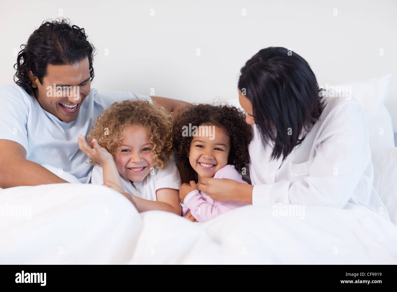 Smiling family sitting on the bed Stock Photo - Alamy