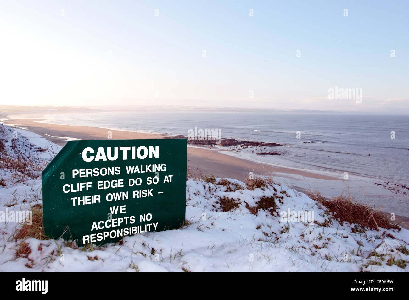 a caution sign on a cliff edge in snow covered ballybunion Stock Photo ...