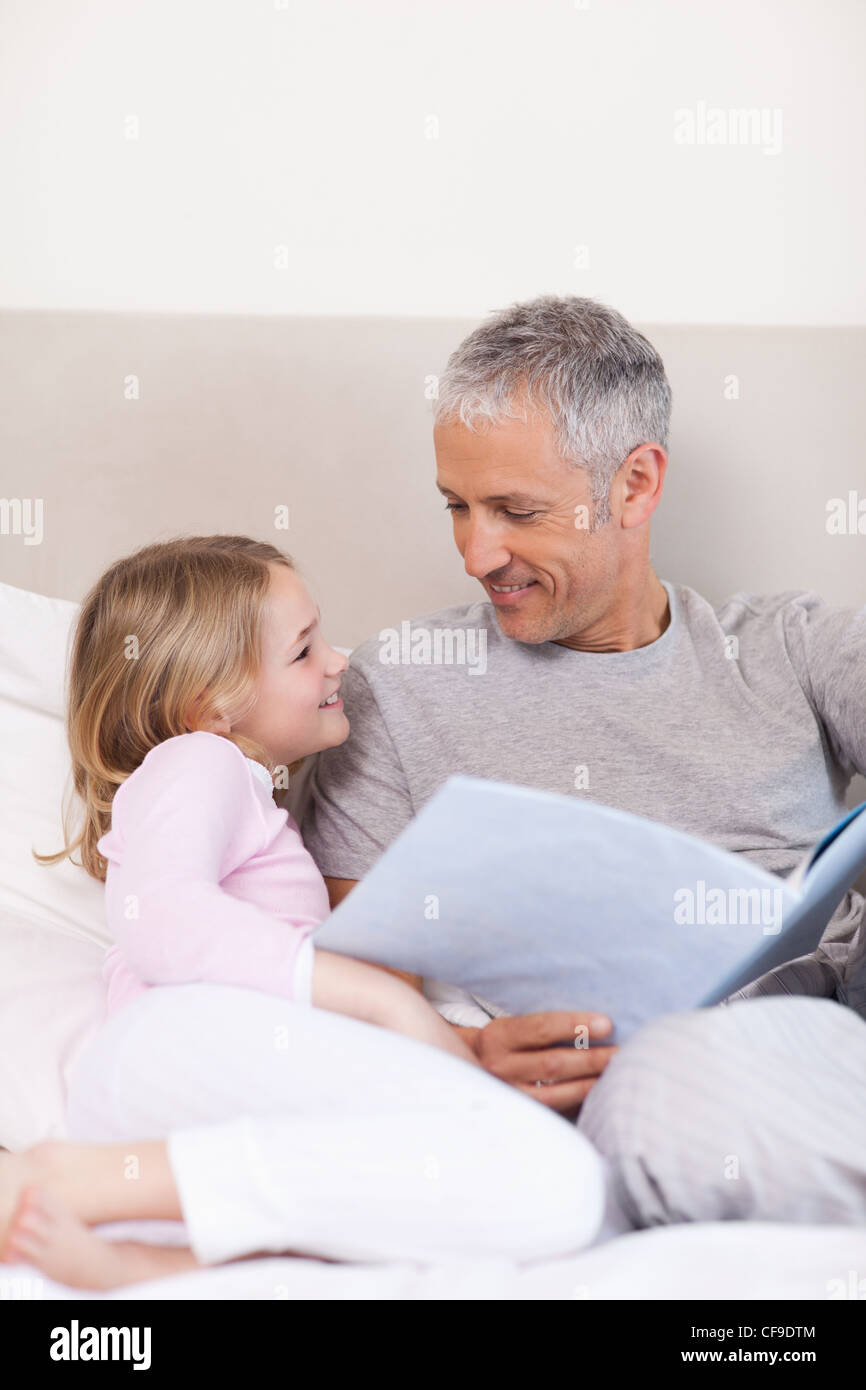 Portrait of a smiling father reading a story to his daughter Stock ...