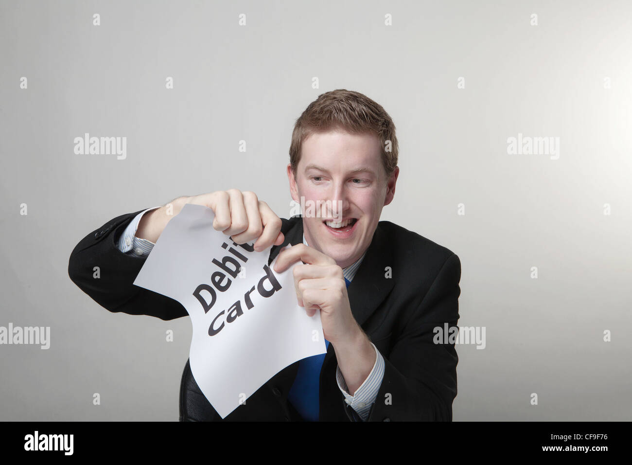 man in a suit sat at a desk ripping a piece of paper up with the words ...