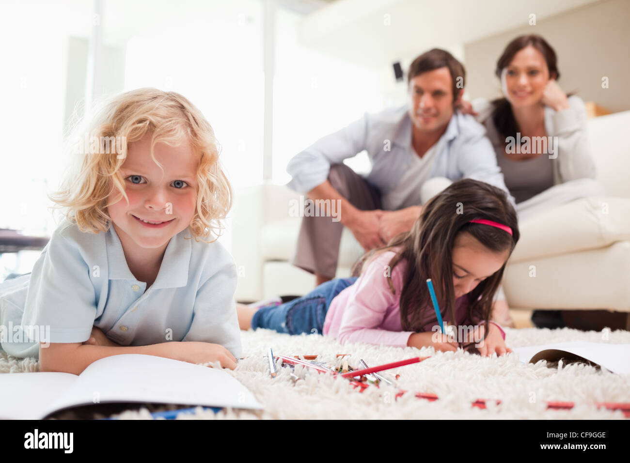 Siblings drawing while their parents are in the background Stock Photo ...