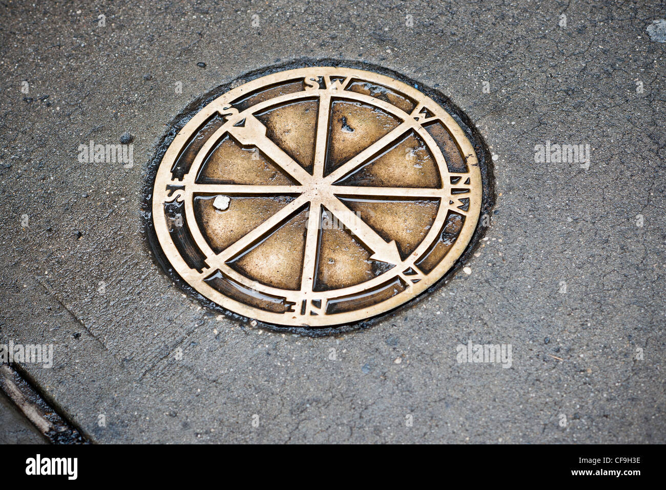 A brass compass is embedded in the sidewalk outside the Wall Street ...