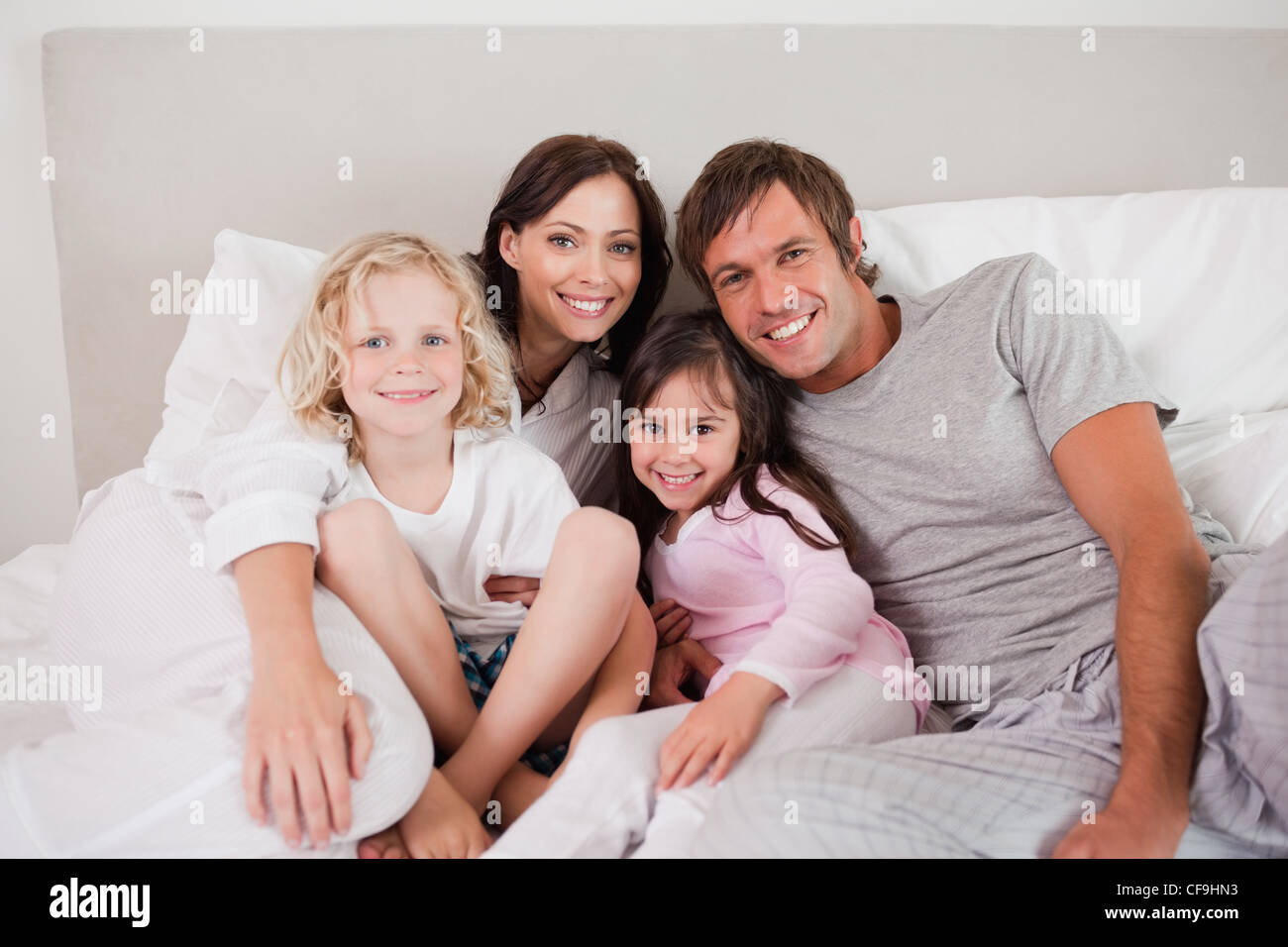 Happy family posing on a bed Stock Photo - Alamy