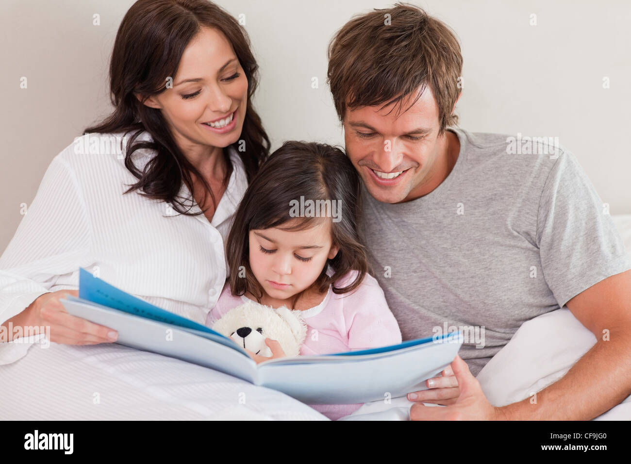 Happy parents reading a story to their daughter Stock Photo - Alamy
