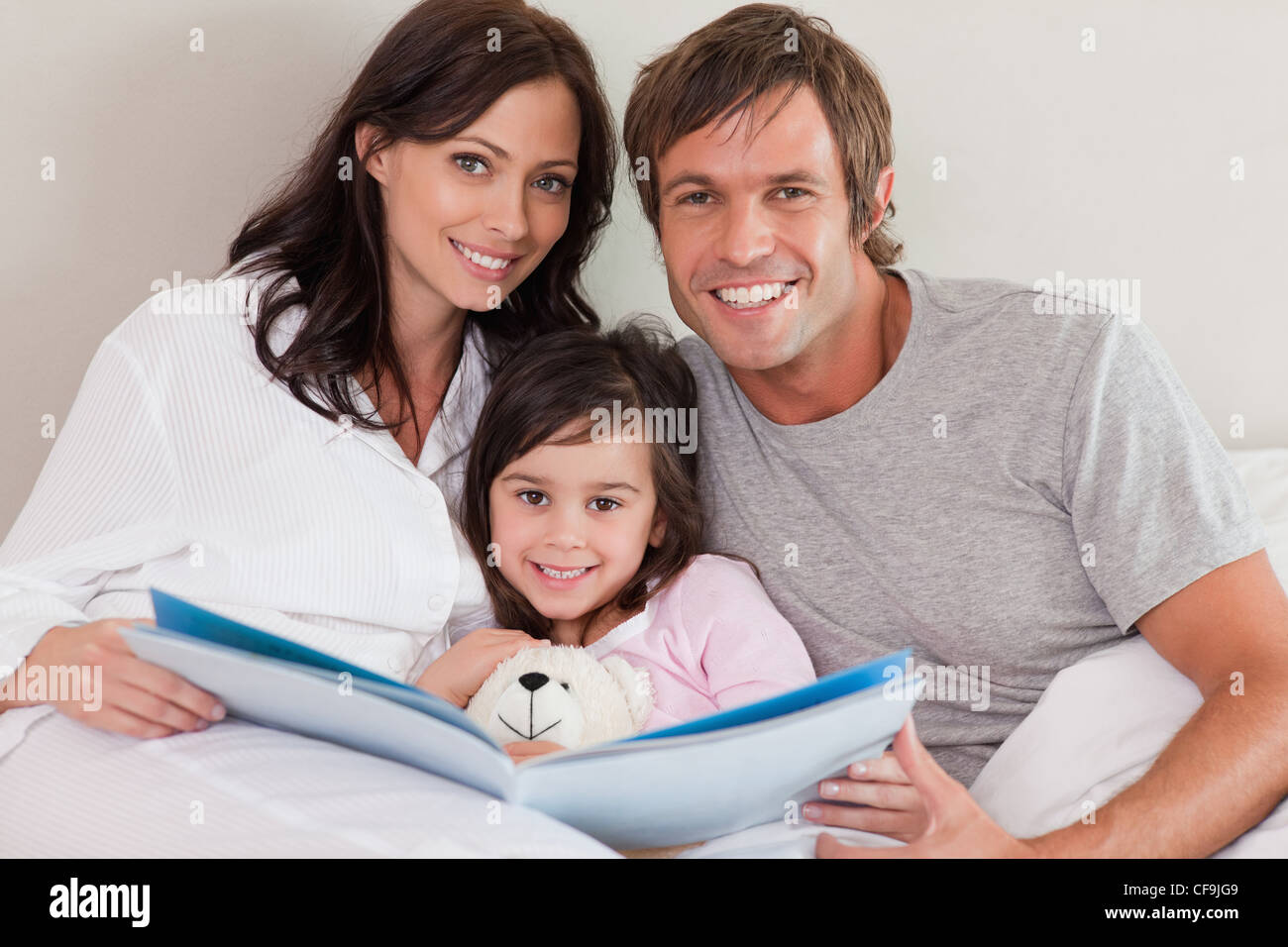 Smiling parents reading a story to their daughter Stock Photo - Alamy