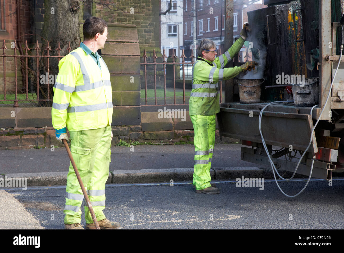 road construction workers installing hot applied high friction road ...