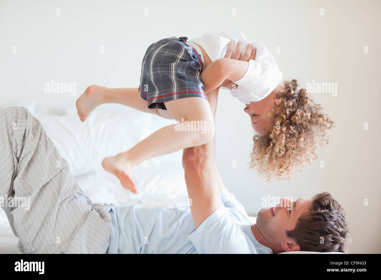 Side view of smiling father lifting child Stock Photo - Alamy