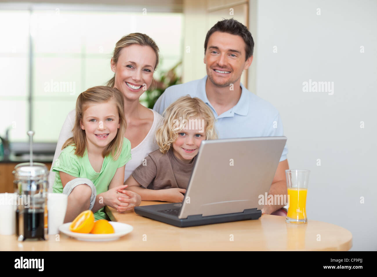 Smiling family using the internet in the kitchen Stock Photo - Alamy