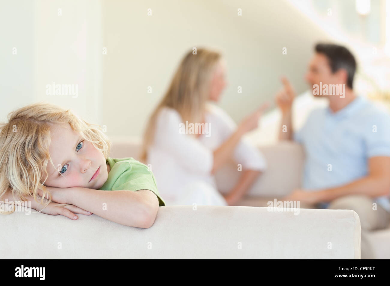 Sad boy with arguing parents behind him Stock Photo - Alamy