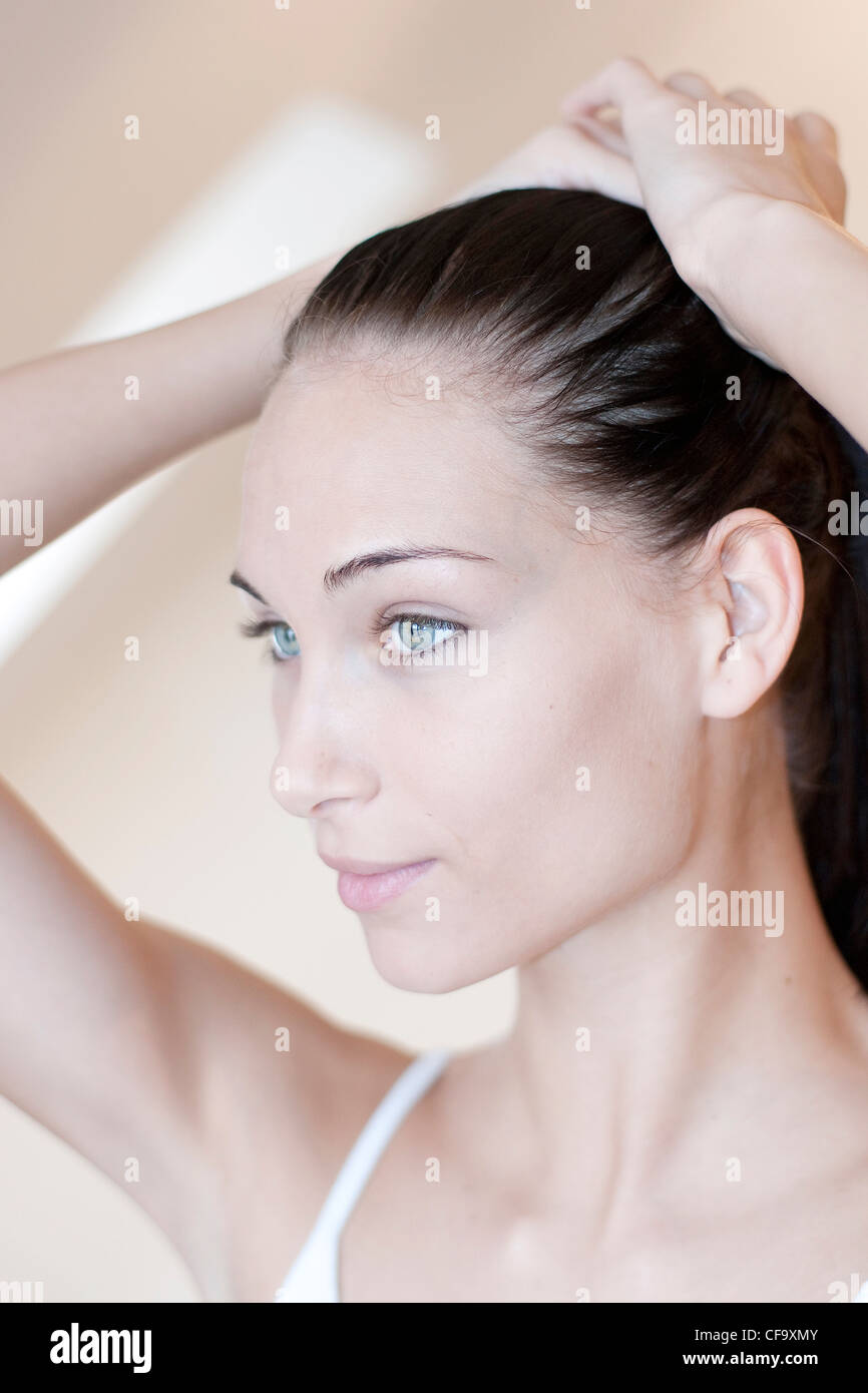 Female holding brunette hair with both hands at the back, unsmiling ...
