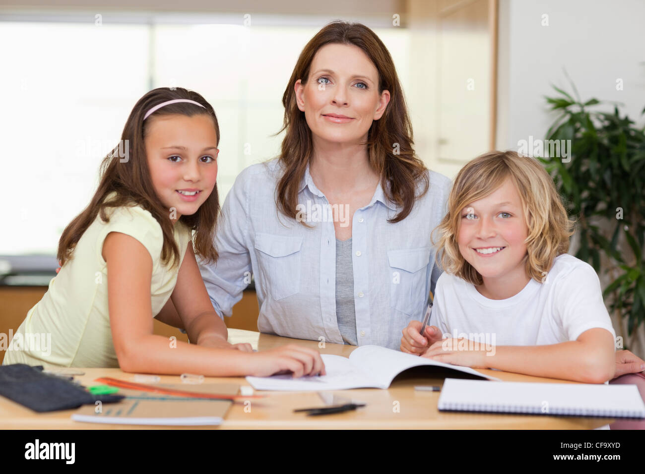 Woman helping her children with homework Stock Photo - Alamy