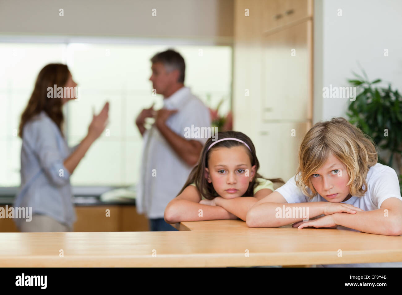 Sad looking siblings with arguing parents behind them Stock Photo - Alamy