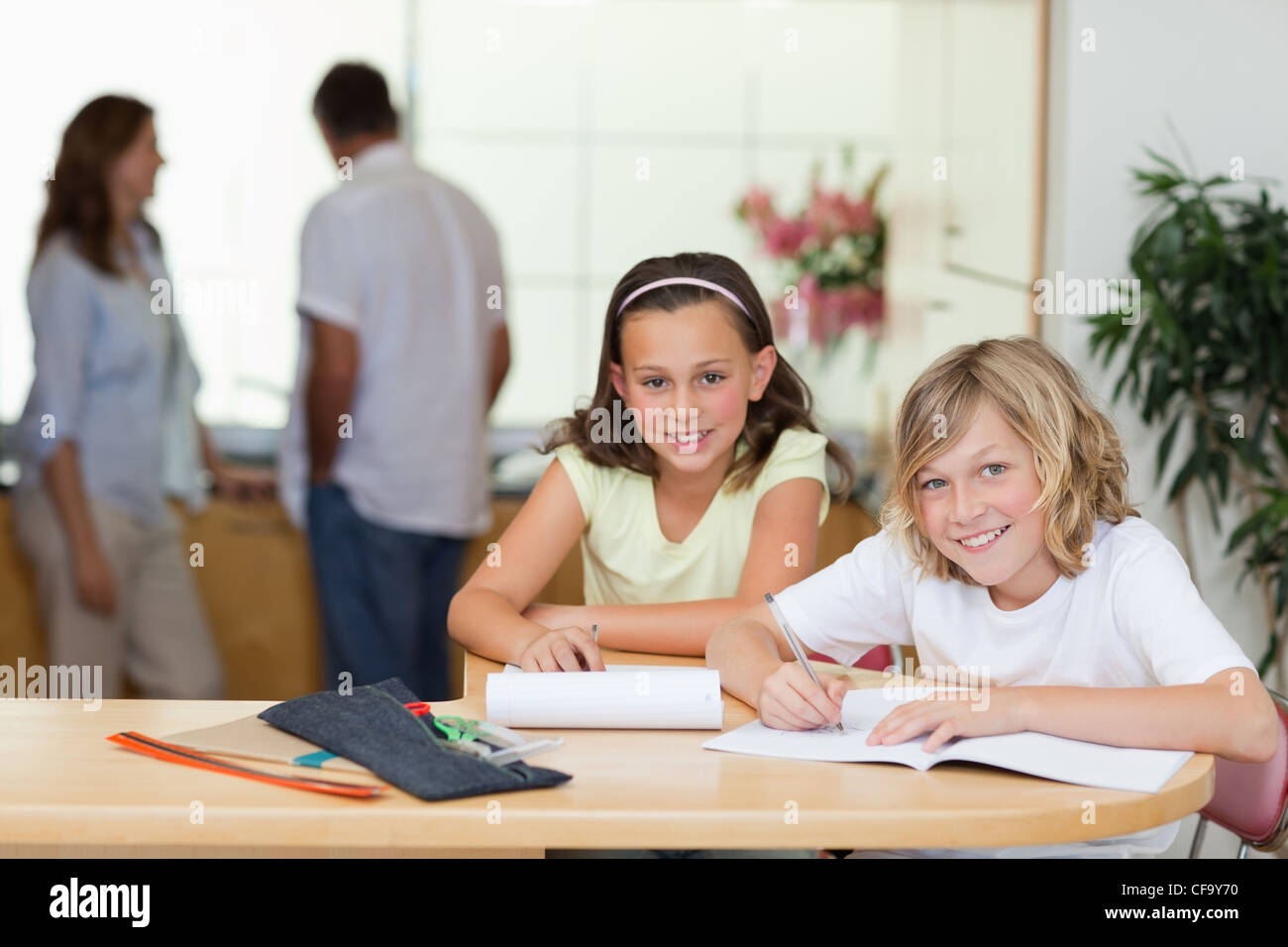 Siblings doing homework with their parents behind them Stock Photo - Alamy