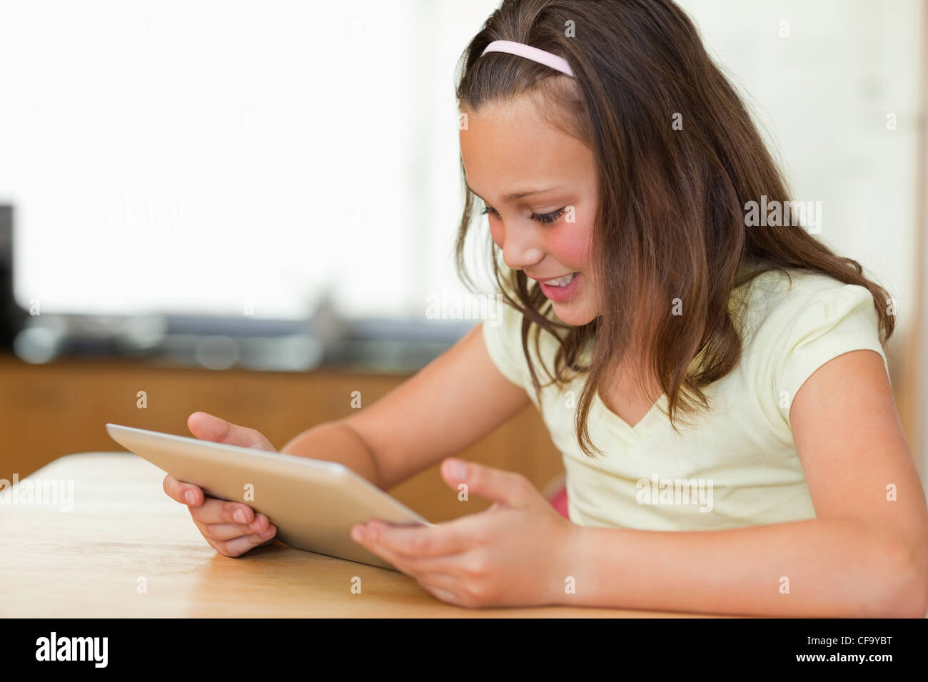 Girl at kitchen table looking at tablet Stock Photo - Alamy