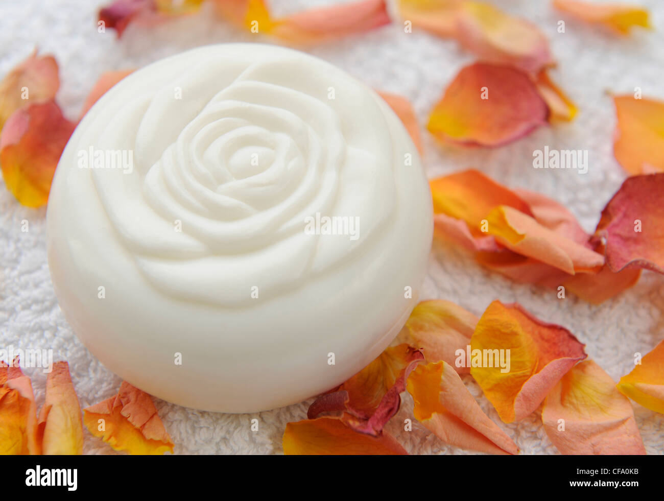 A white round bar of soap with a rose shaped pattern on the top of them ...