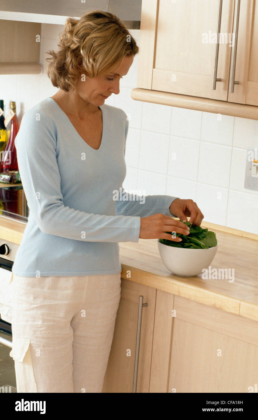 Female short fair hair, wearing a blue v neck top and white trousers ...