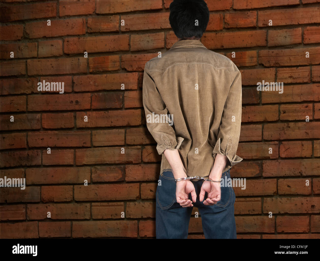 Young man in handcuffs stands in front of brick wall Stock Photo - Alamy