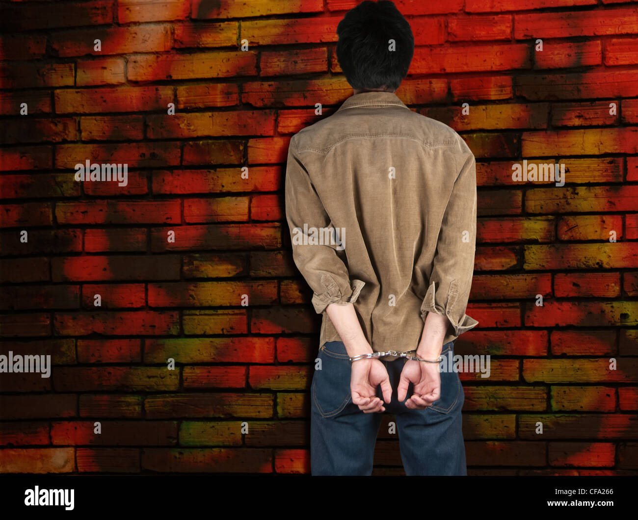 Young man in handcuffs stands in front of brick wall Stock Photo - Alamy
