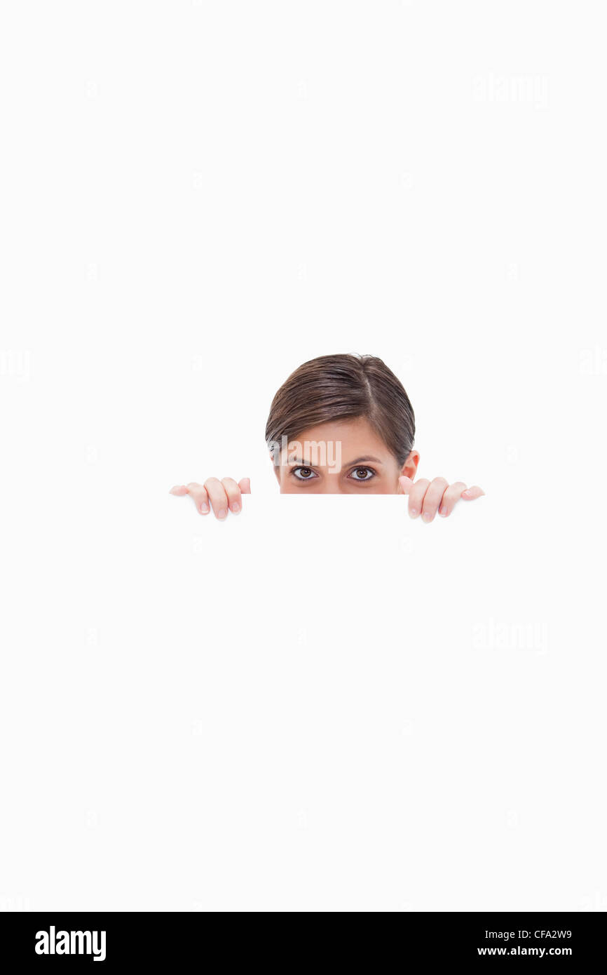 Sneaky woman looking over blank wall Stock Photo - Alamy