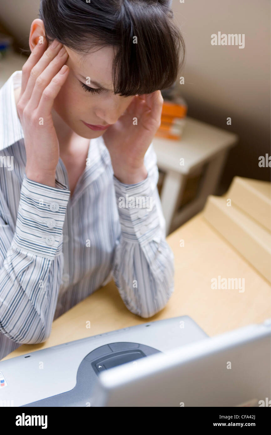 Brunette female her hair swept up sitting at a desk in front on a ...