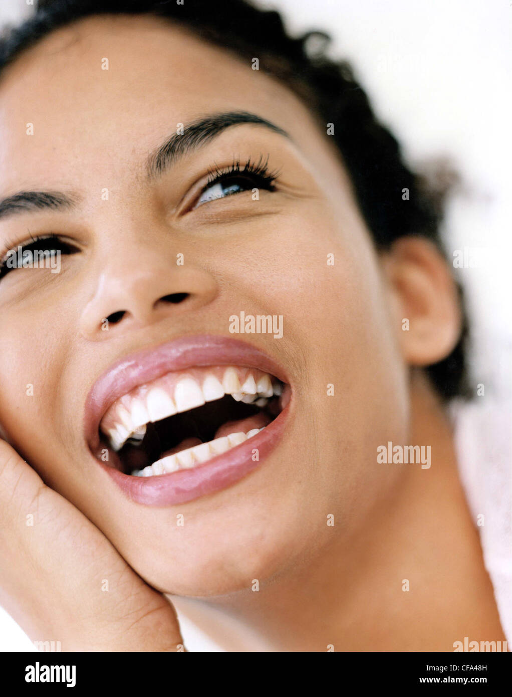 Female with short dark curly hair head tilted back, hand on cheek ...