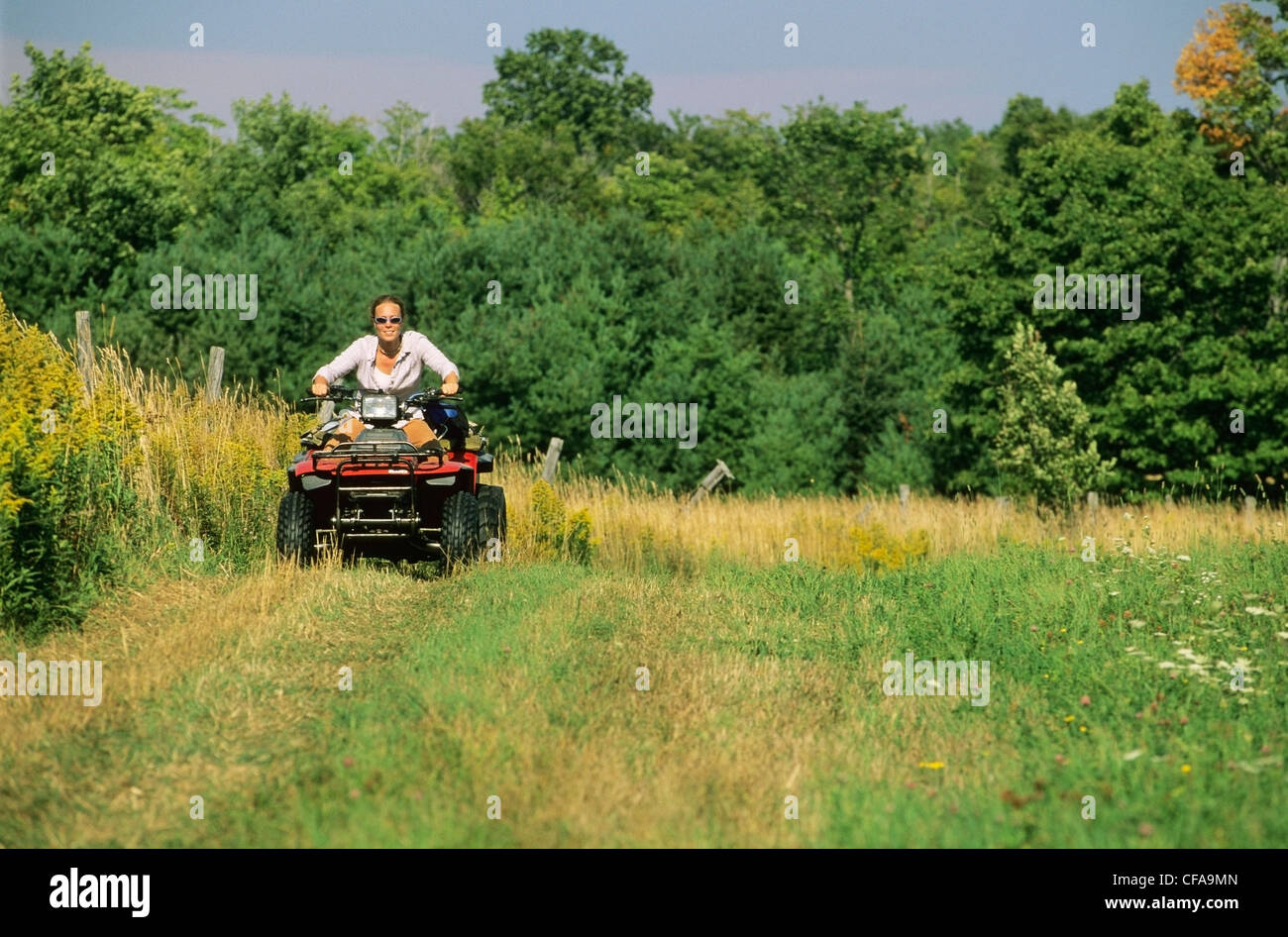 Woman rides a quad ATV on a farm, Manitoulin Island, Ontario, Canada ...