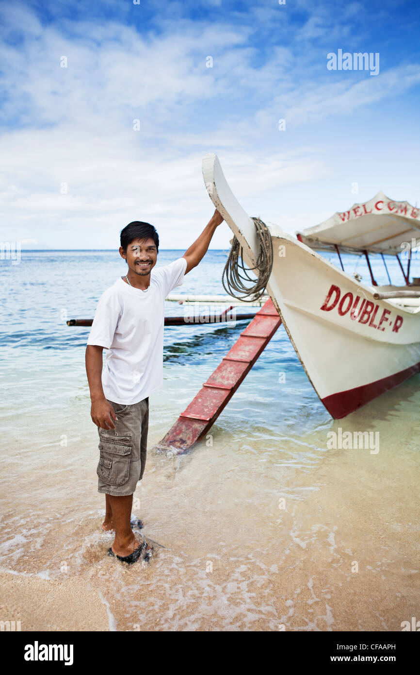 Man with boat on tropical beach Stock Photo - Alamy