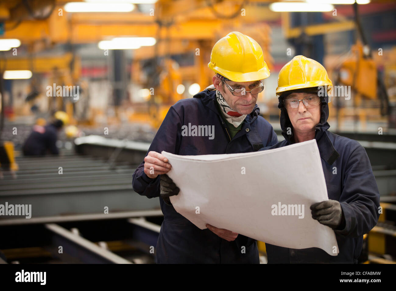Workers reading blueprints in shipyard Stock Photo - Alamy