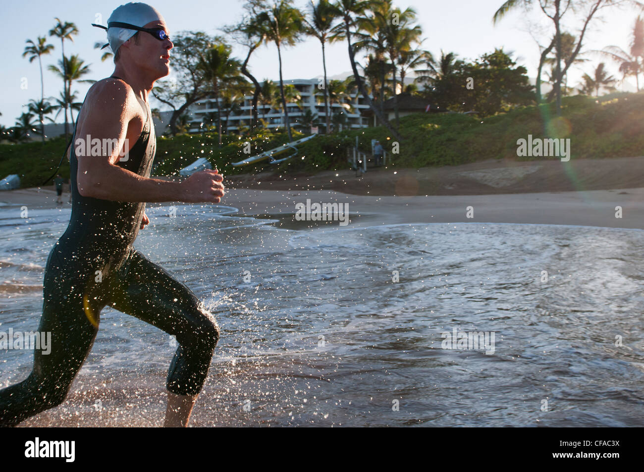 Swimmer running in waves on beach Stock Photo - Alamy