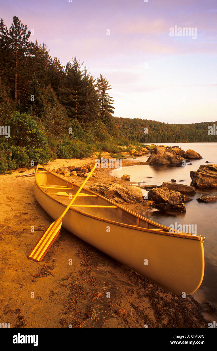 A canoe with paddle at sunrise, during summer, on the shore of Booth ...