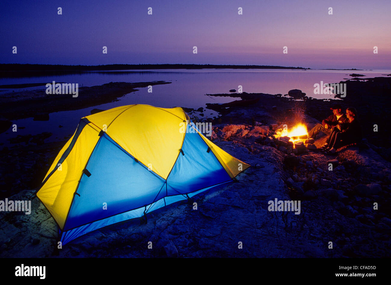 Campers enjoy a campfire at sunset, on the shore of Lake Huron, near ...