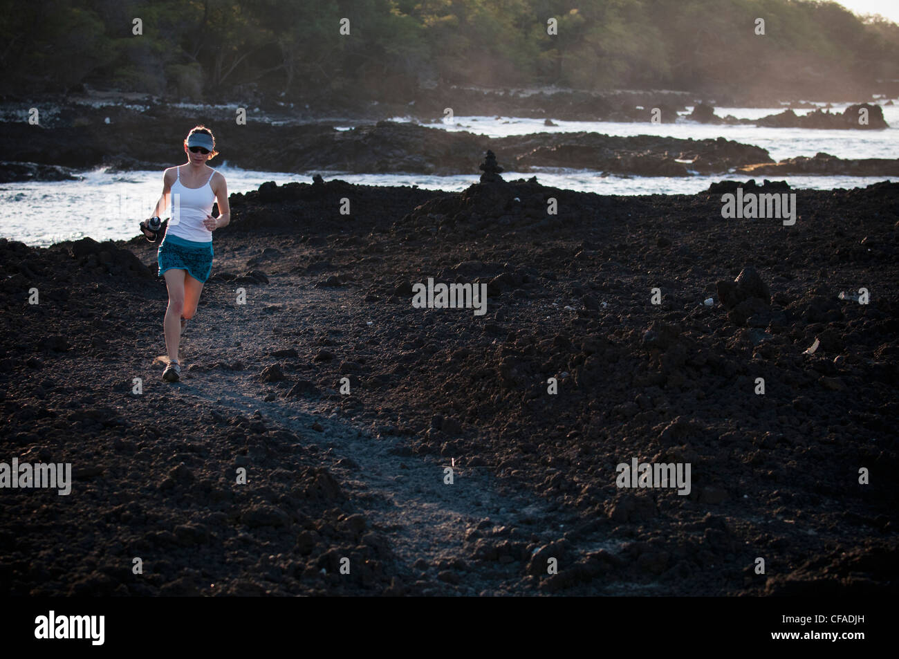 Woman running on rocky beach Stock Photo - Alamy