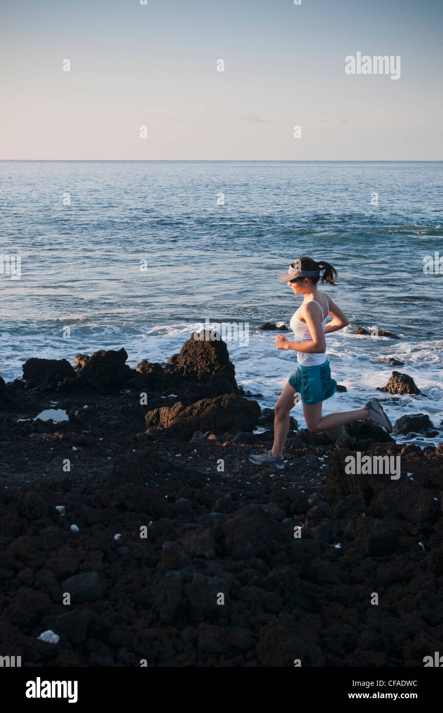 Woman running on rocky beach Stock Photo - Alamy