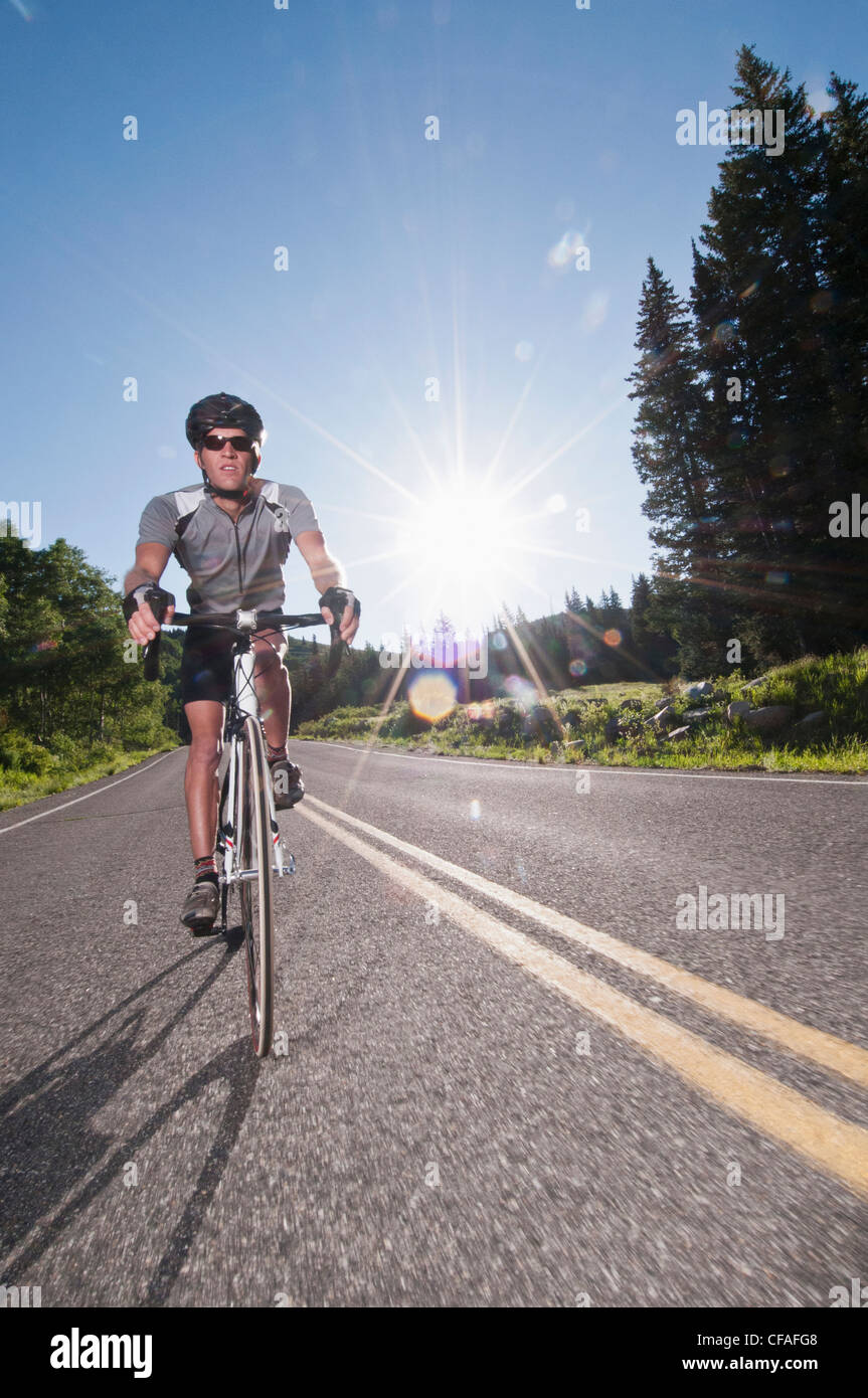 Cyclist biking on rural road Stock Photo - Alamy