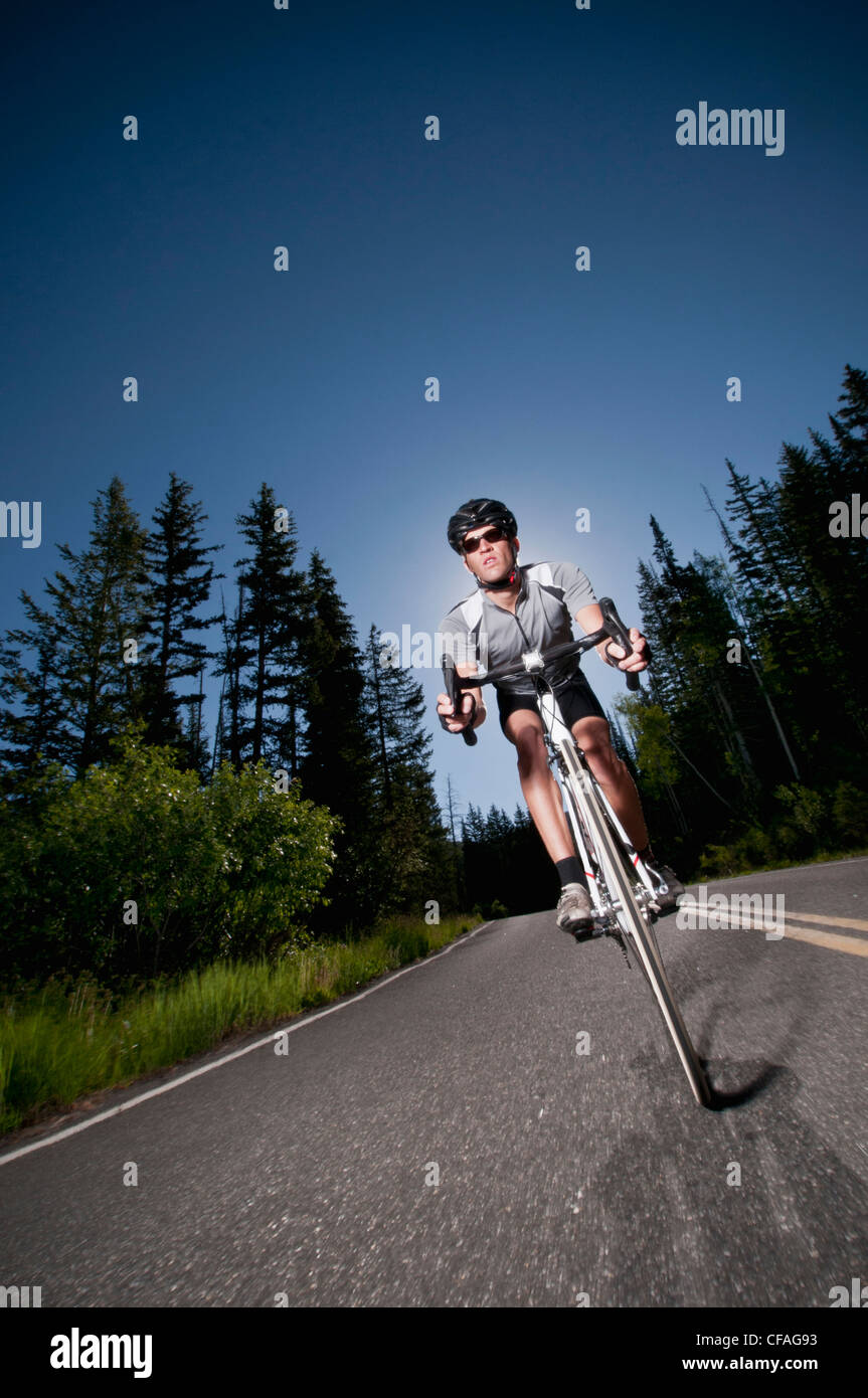 Cyclist biking on rural road Stock Photo - Alamy