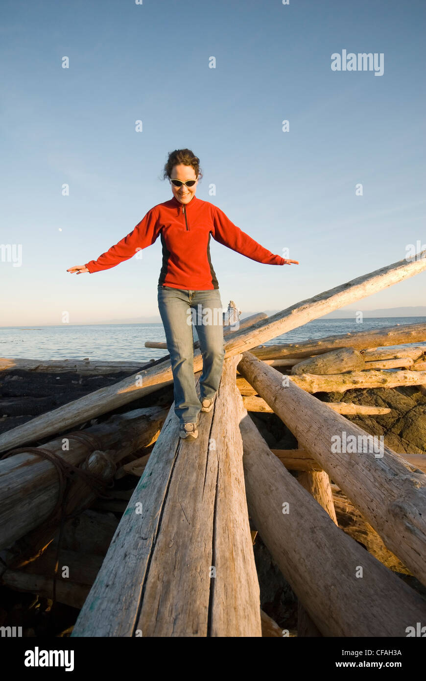 A woman balances on a drift log on the beach near Victoria, Vancouver ...