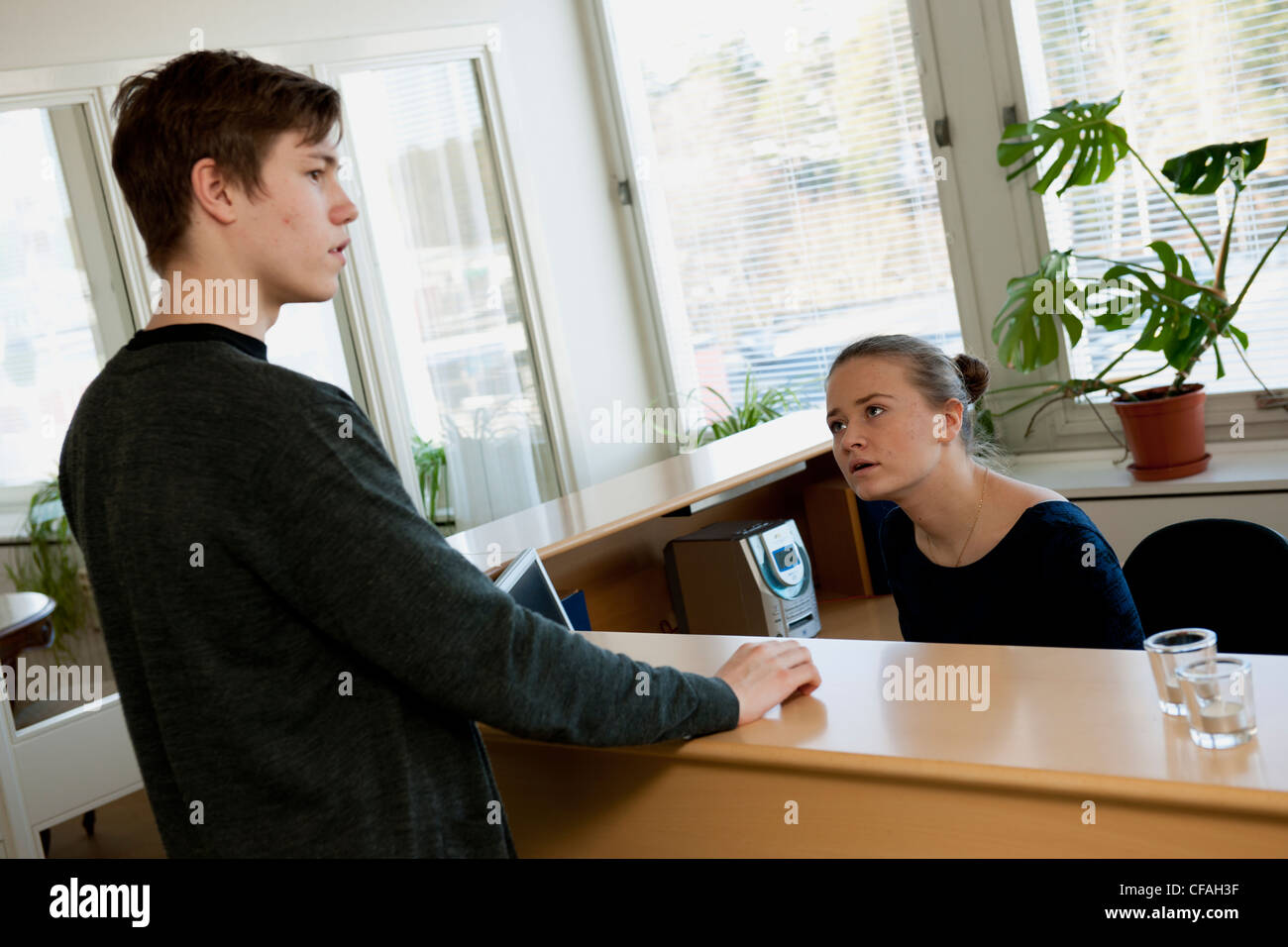 Young man asking a question at an information desk Stock Photo - Alamy