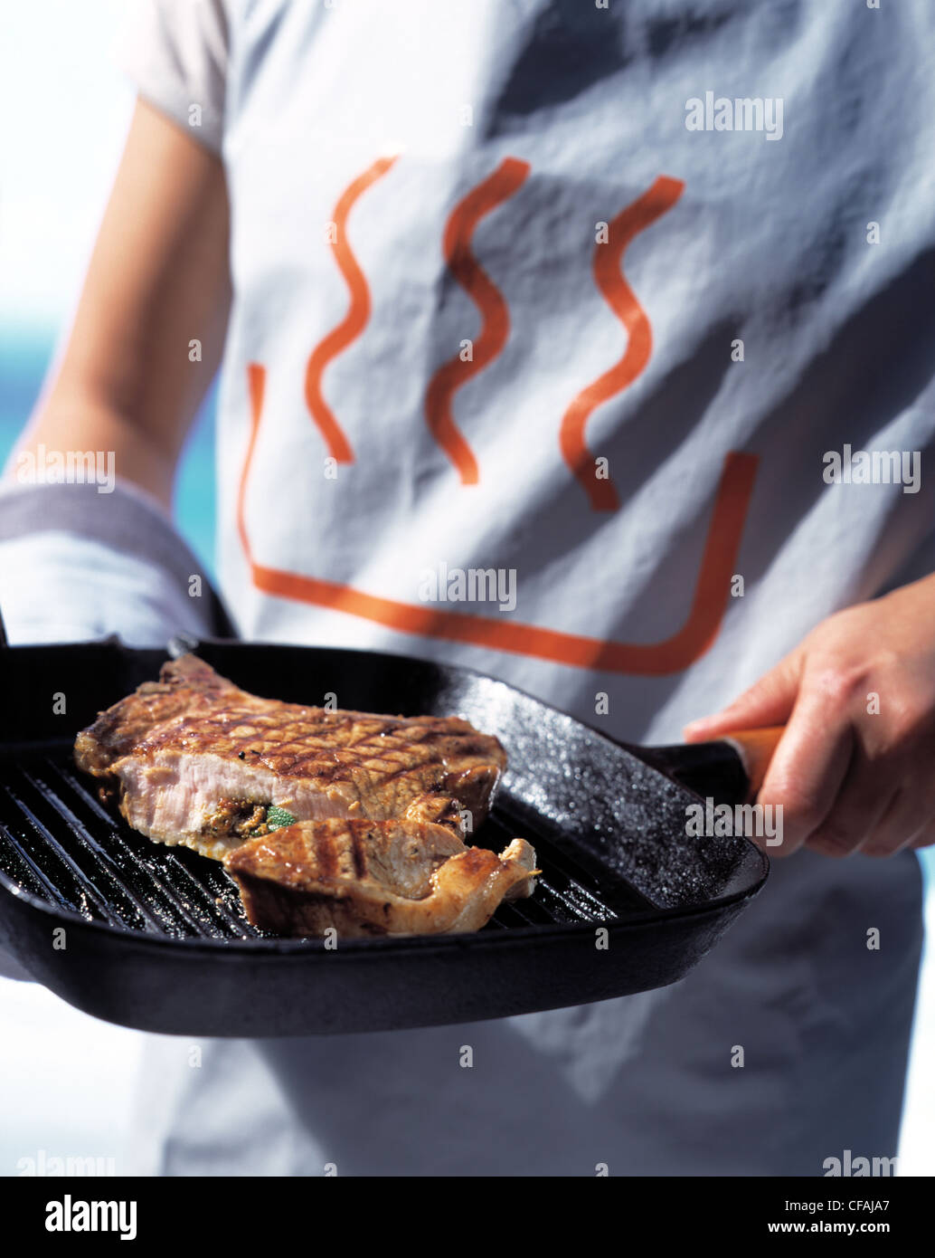 Man holding grilled pork chop in a pan Stock Photo - Alamy