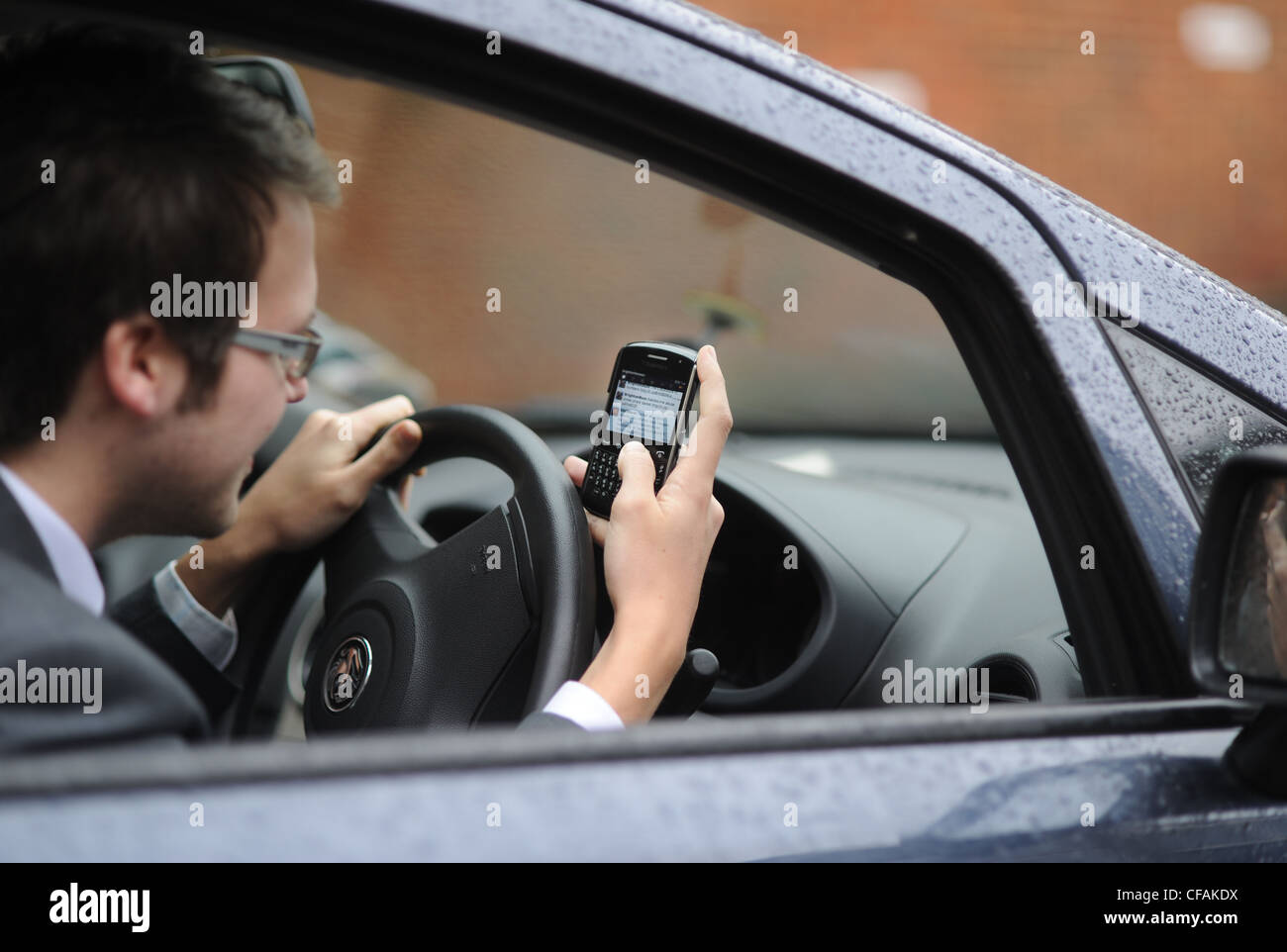 Posed by Model - A car driver using a Blackberry mobile telephone to ...