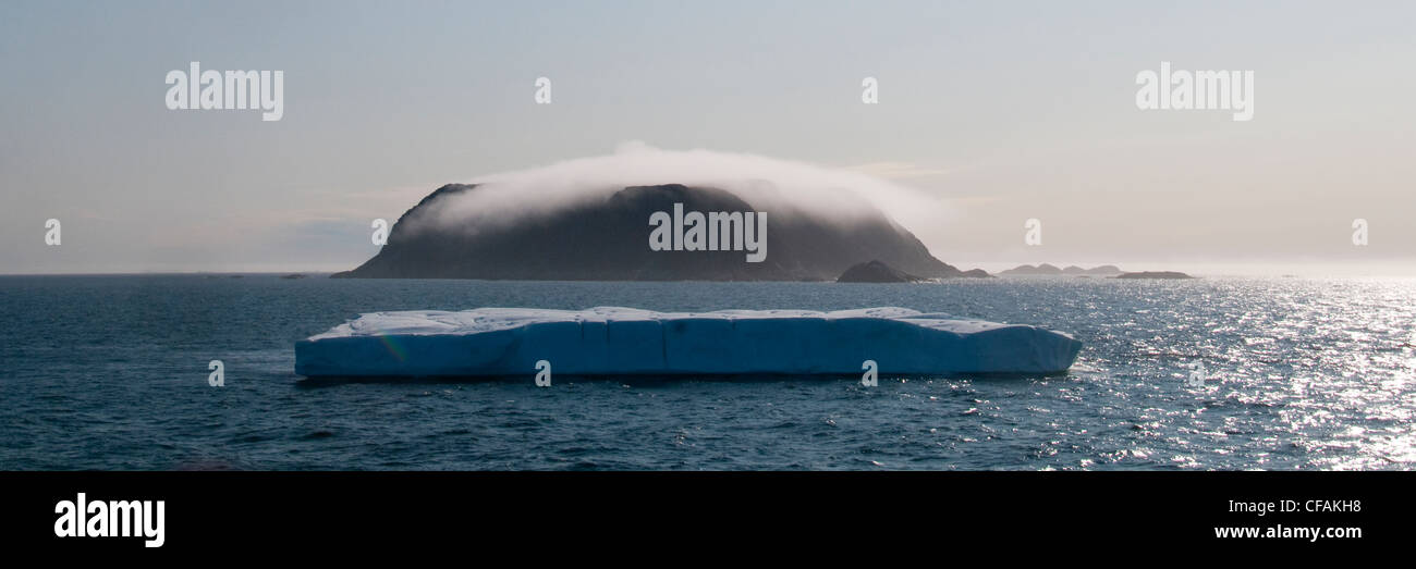 Iceberg floating past a foggy Monumental Island in the Davis Strait off ...