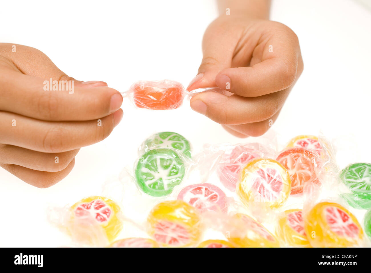 Unwrapping a candy with hands on white background Stock Photo - Alamy