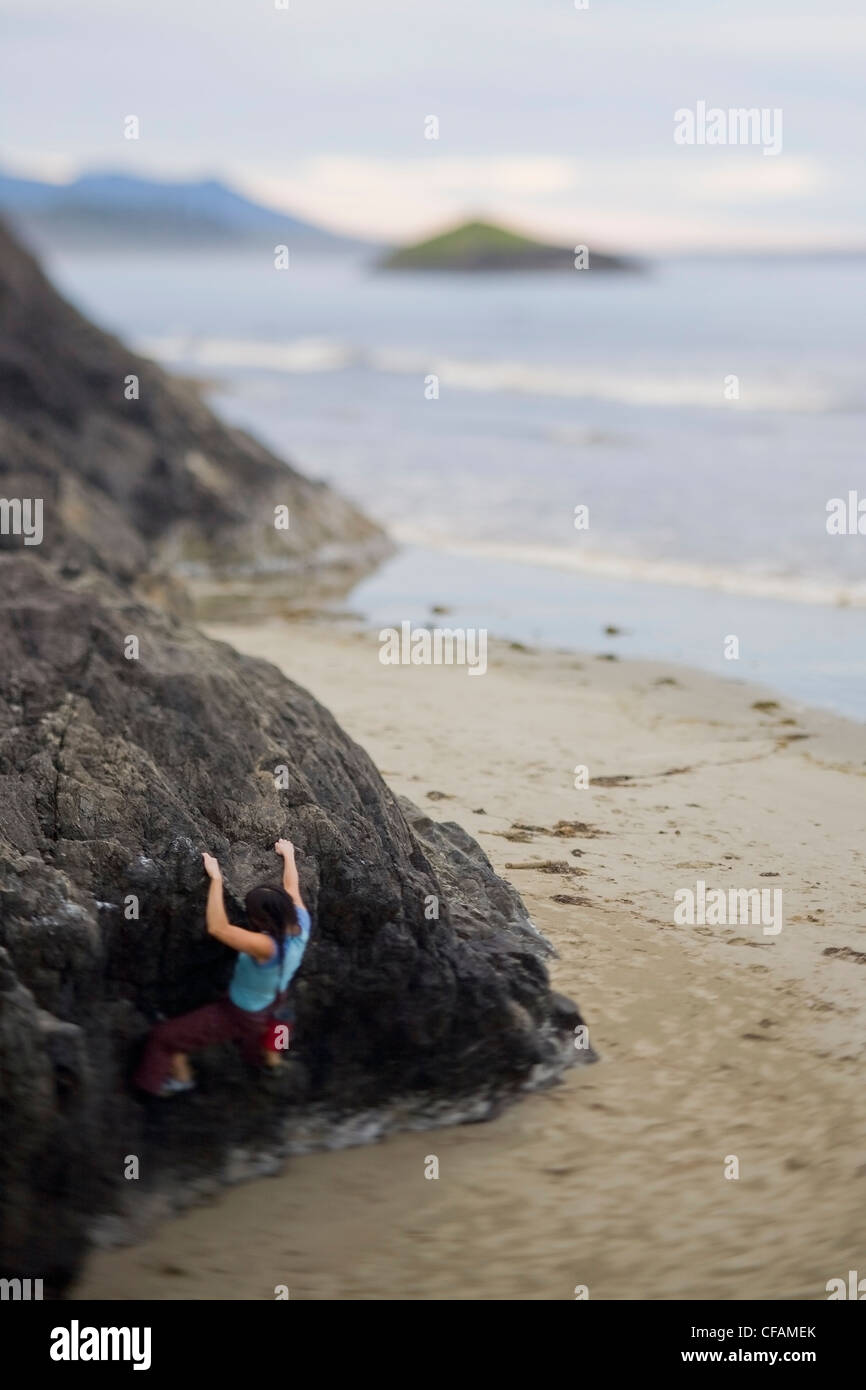 A young female bouldering oceanside in Tofino, Vancouver Island ...