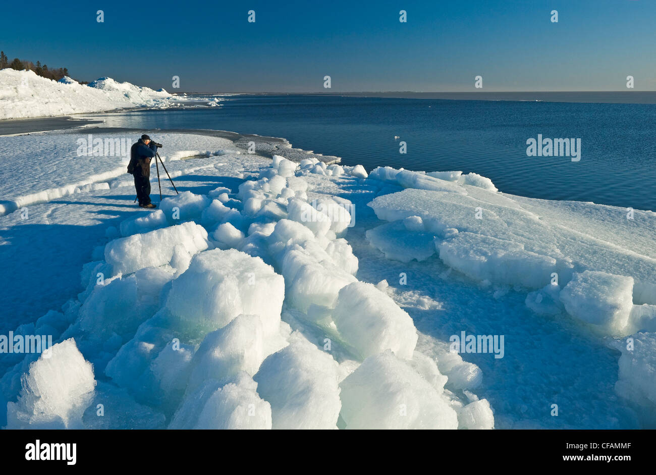 a photographer takes photos of washed up ice piles, along Lake Winnipeg ...
