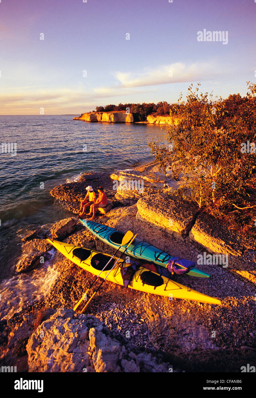 Couple relaxing along limestone cliffs with kayaks, Steep Rock Beach ...